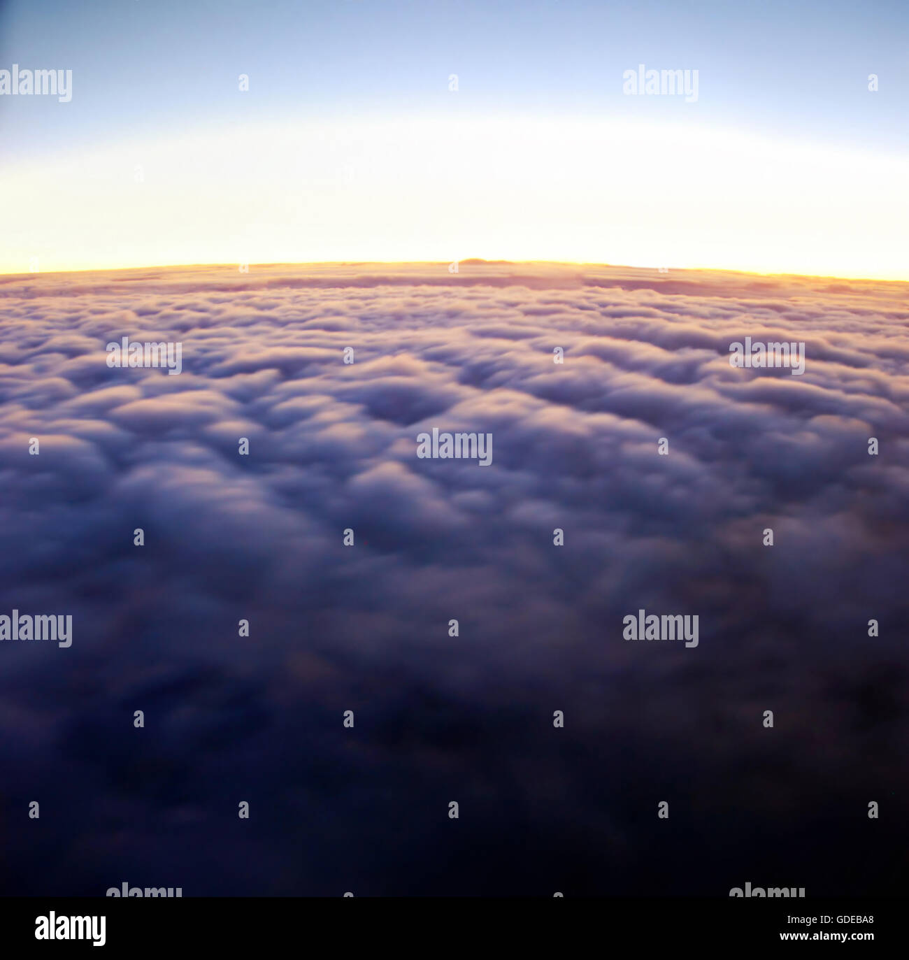 Sun beginning to rise above layer of clouds Stock Photo - Alamy