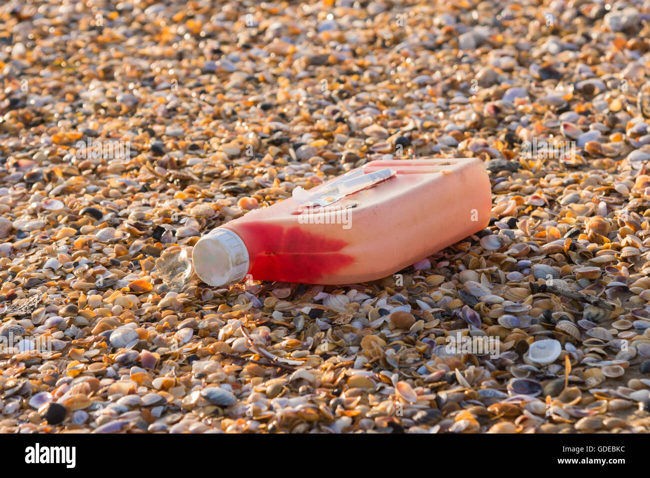 Plastic bottles of engine oil on the beach is strewn with small ...