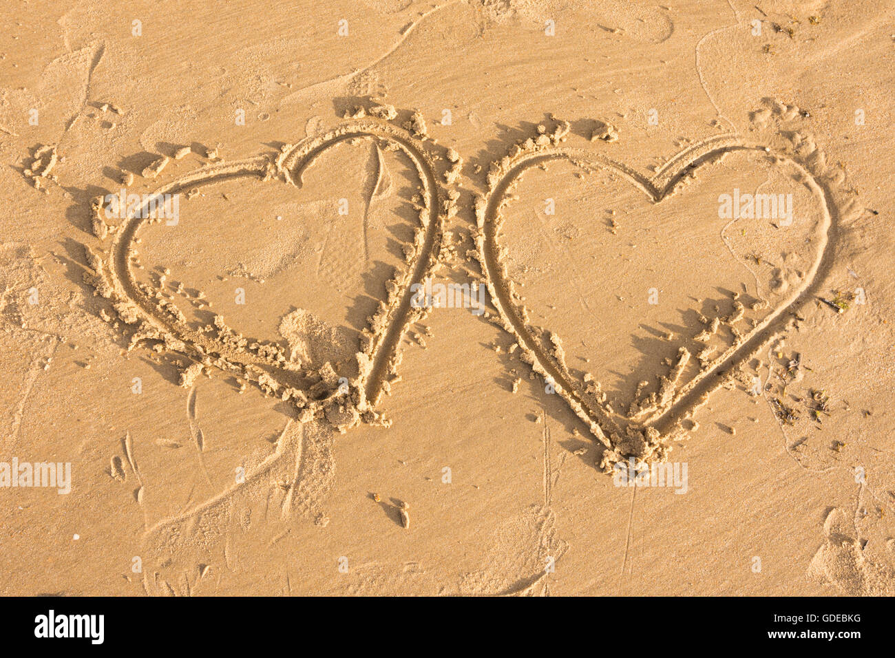 Two hearts drawn in the sand on the sea beach Stock Photo - Alamy