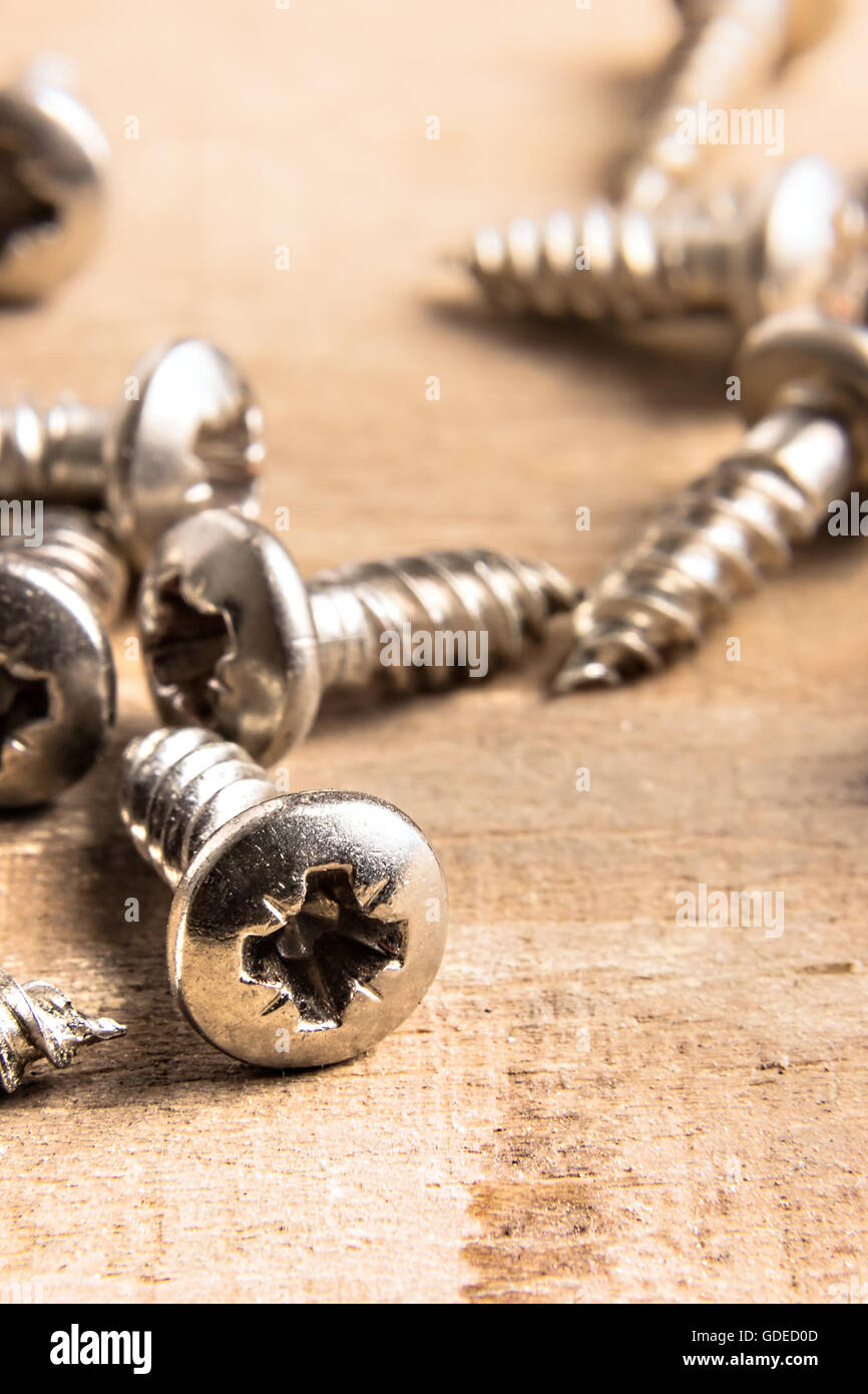 Metal screws close up in a wooden table. Vertical image Stock Photo - Alamy