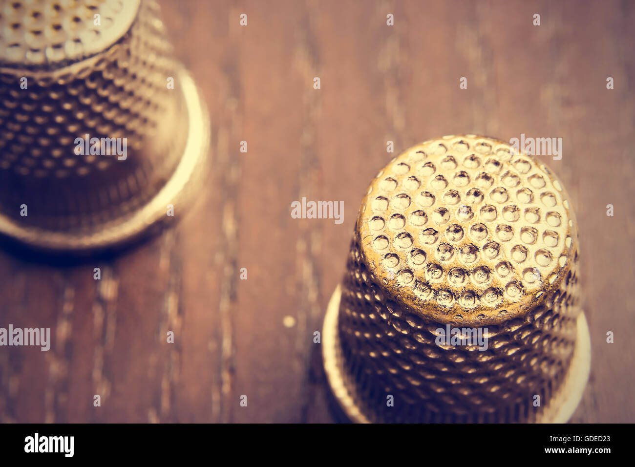 Thimble close up on a brown wooden table. Vintage style. Horizontal ...