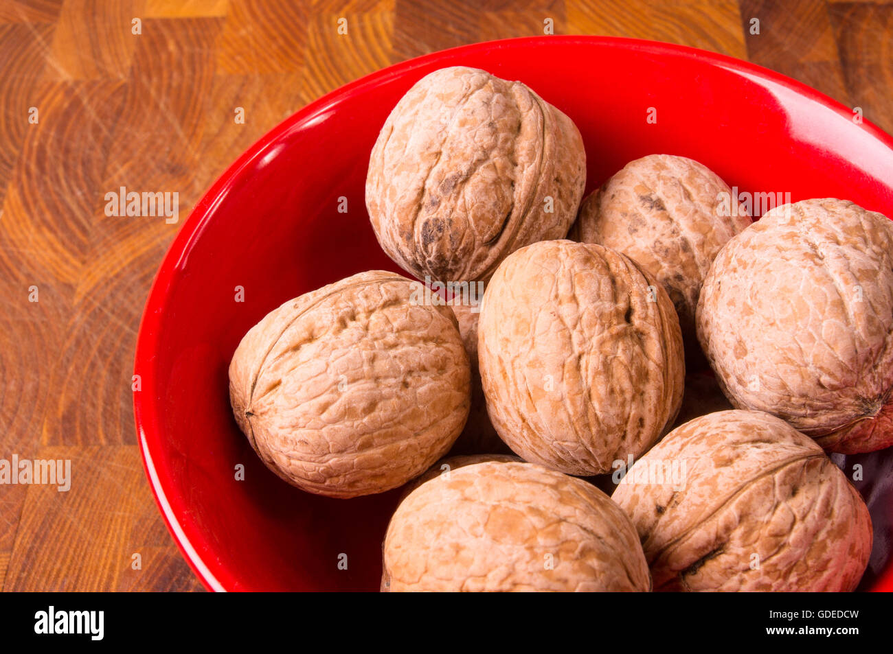 walnuts in red plate on wooden background Stock Photo - Alamy