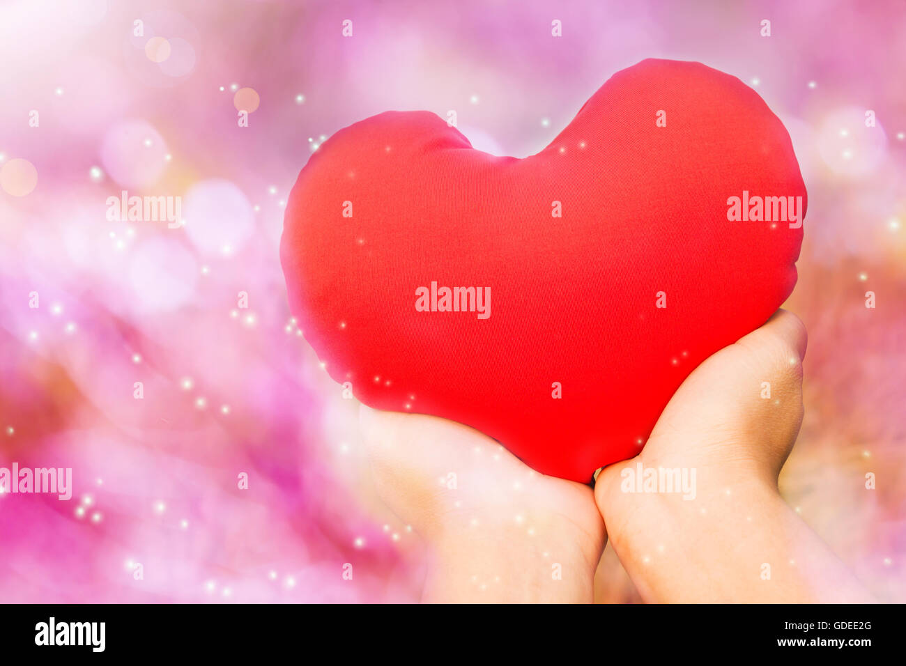 Hand give or raise big red heart in dreamy glow shining glitter on ...