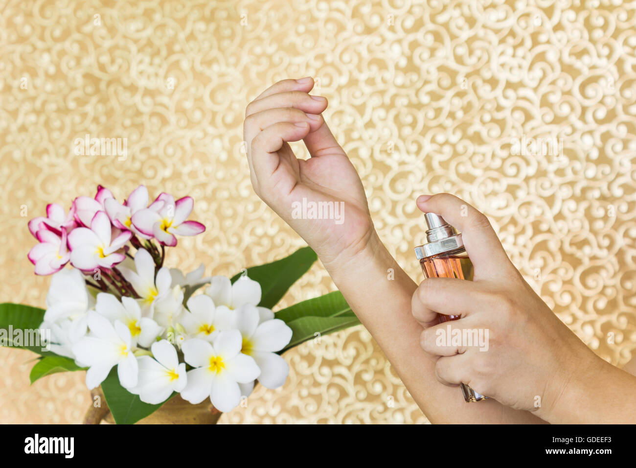 Women hand spraying perfume at wrist with flowers in vase and classic ...