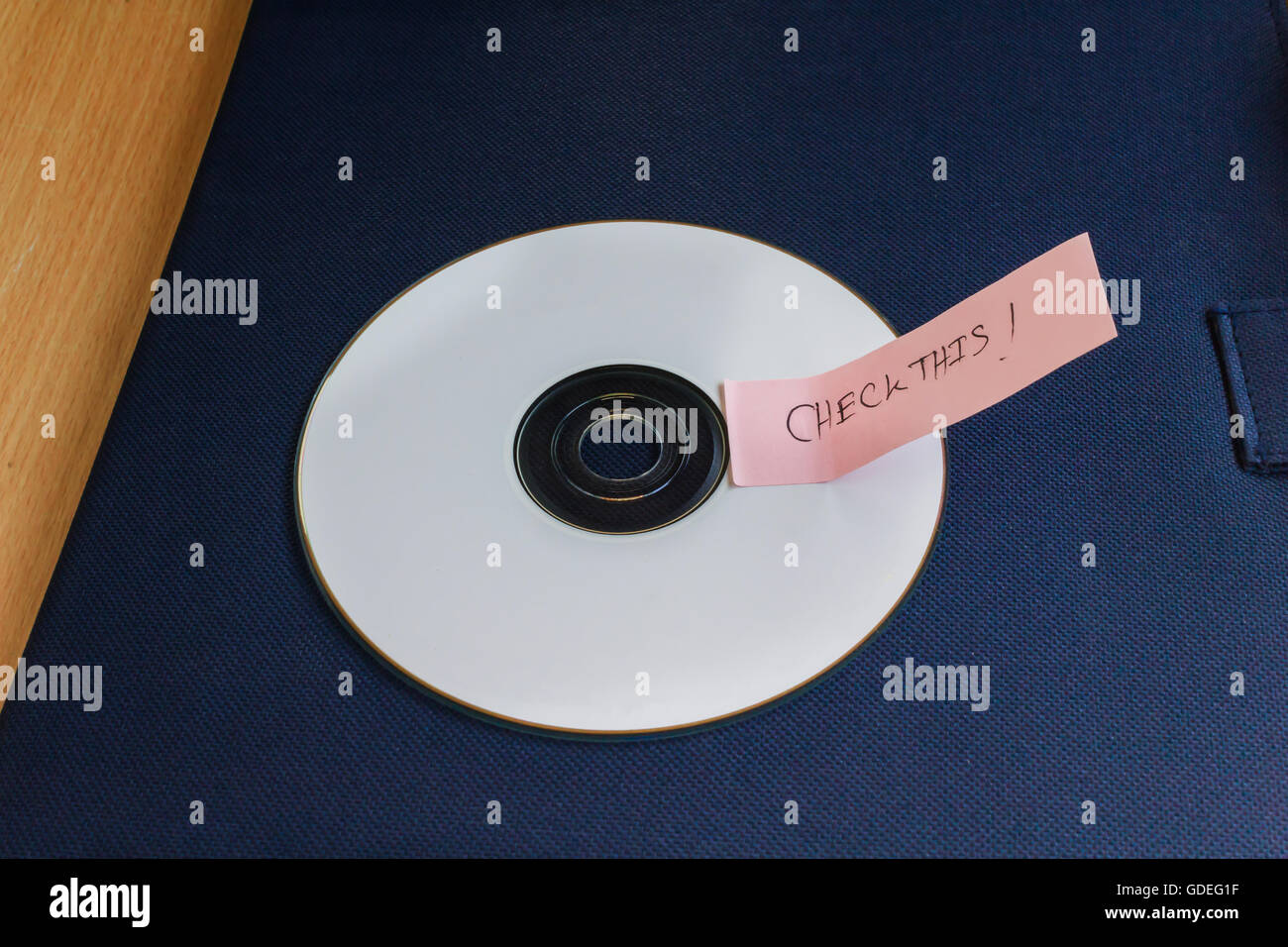 White CD or compact disk with note text word check this on dark blue ...