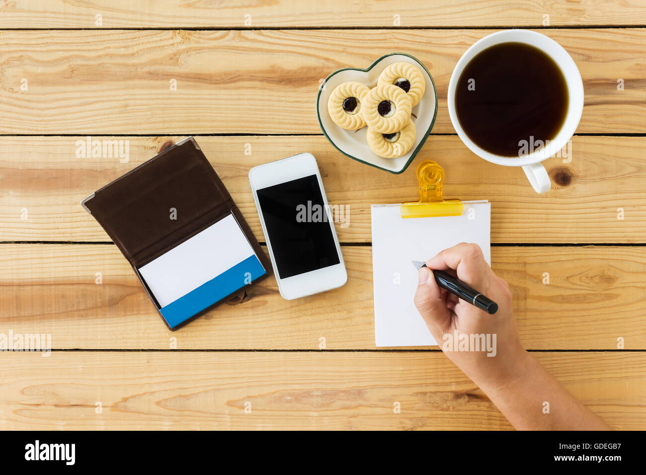 Top view hand with pen, writing down on blank paper note ,cellphone ...