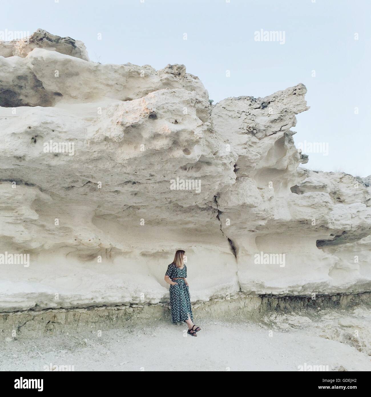 Woman leaning against rocks Stock Photo - Alamy