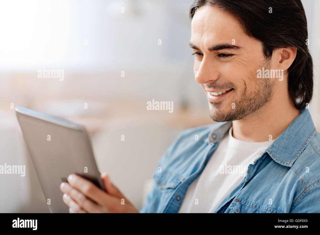 Cheerful smiling man using tablet Stock Photo - Alamy