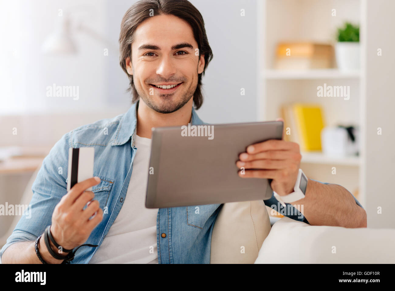Pleasant cheerful man using tablet Stock Photo - Alamy