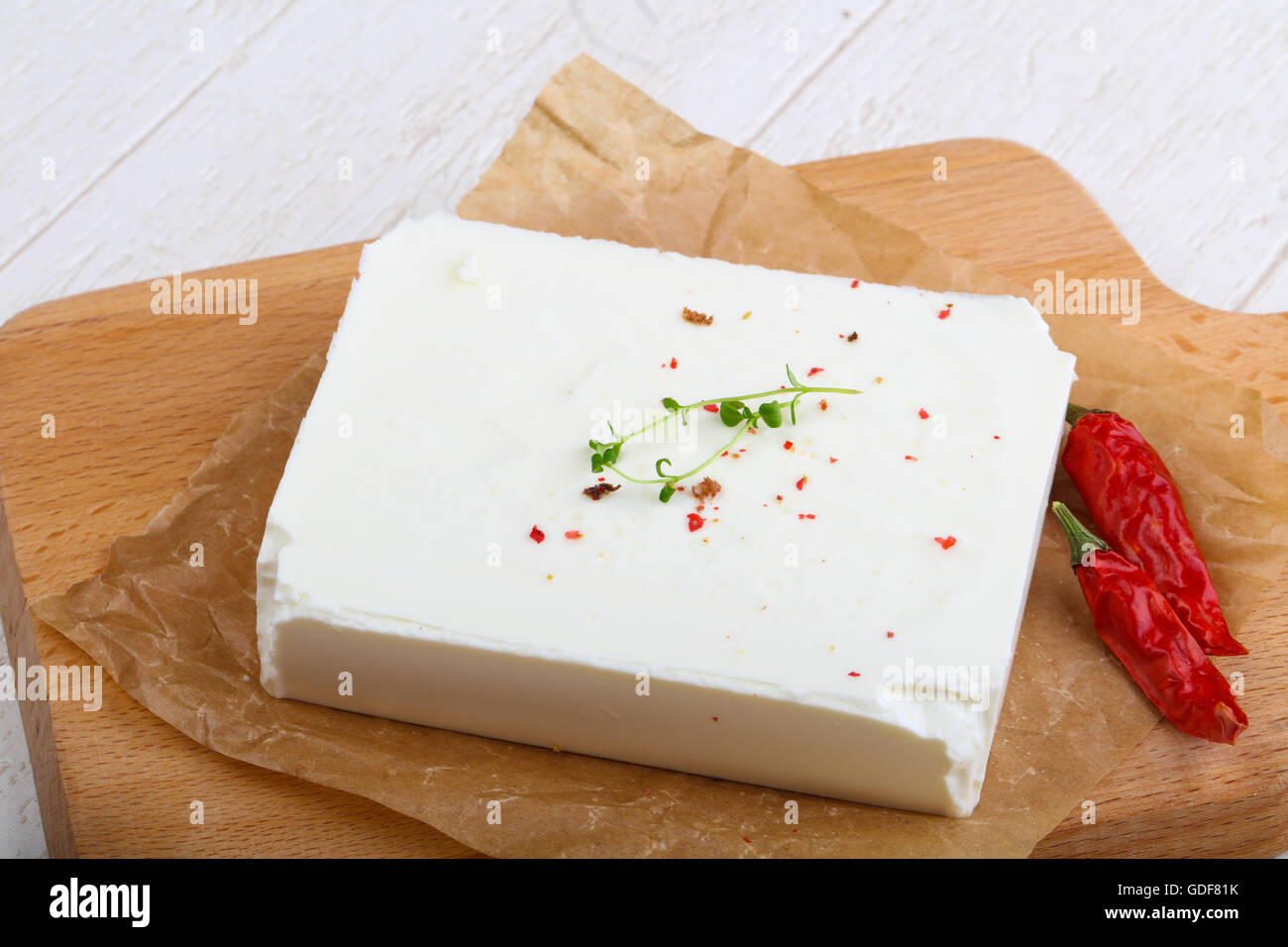 Feta brick cheese on the board wth thyme and pepper Stock Photo - Alamy