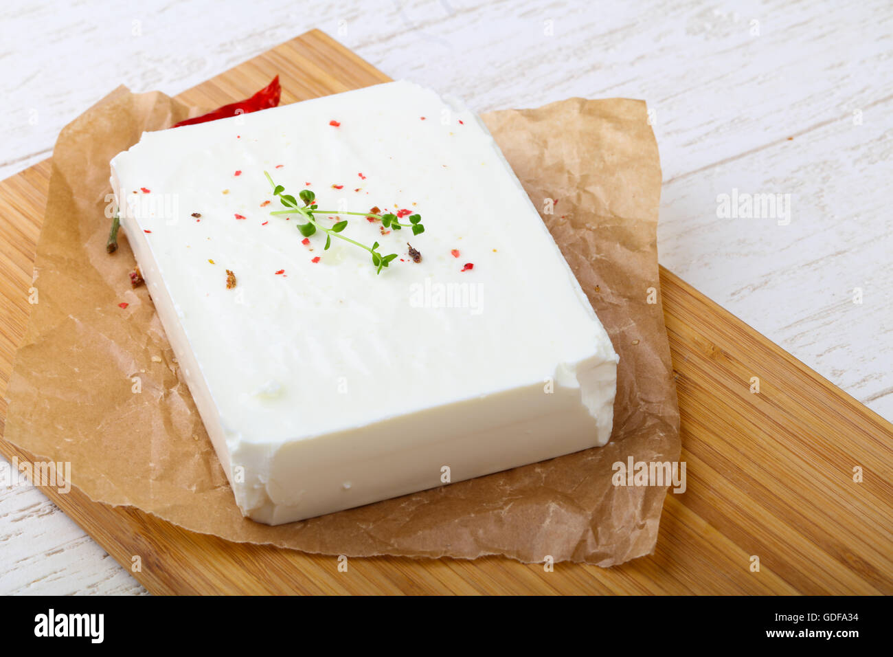 Feta brick cheese on the board wth thyme and pepper Stock Photo - Alamy
