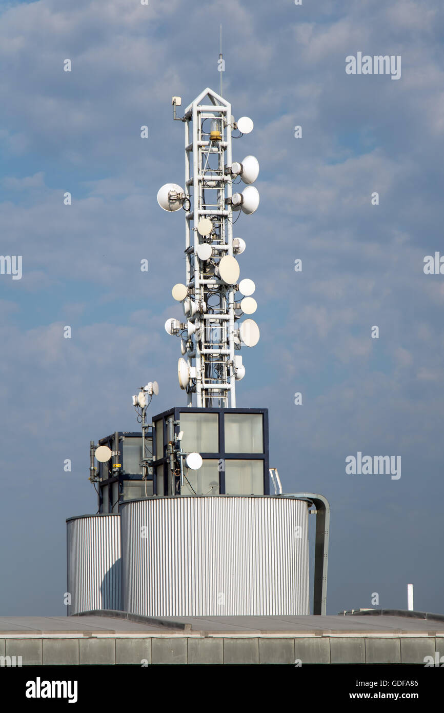 Telecommunication mast with microwave link on top roof at blue sky ...