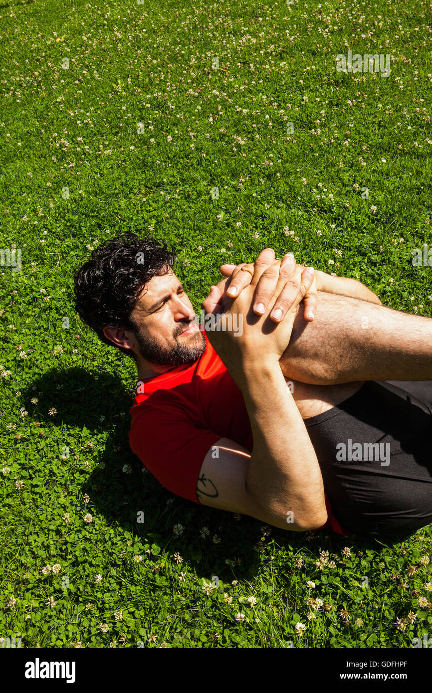 Urban athlete doing stretching exercises on the grass Stock Photo - Alamy