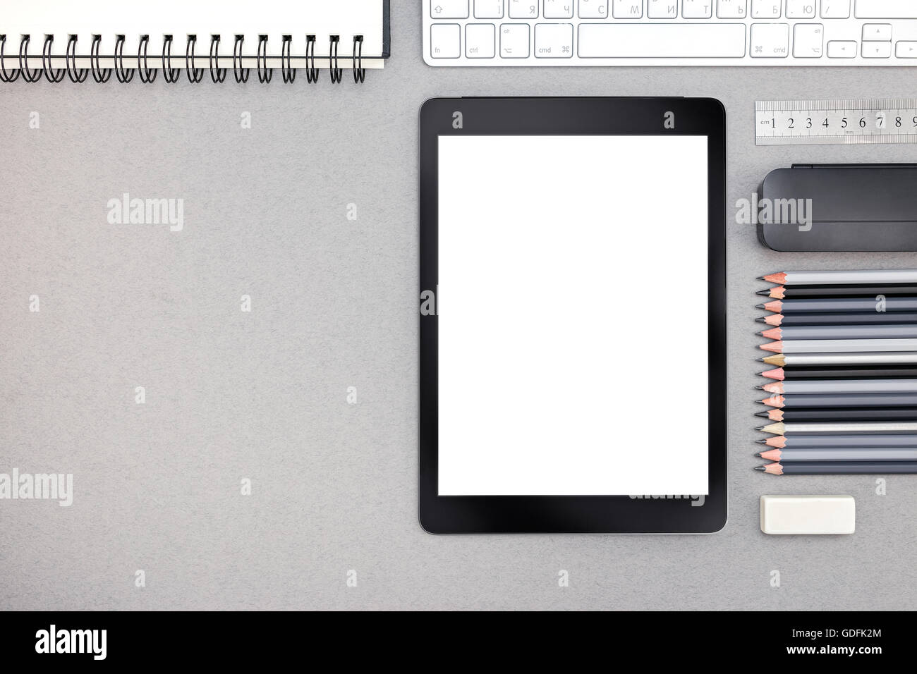 gray desktop with digital tablet, spiral notebook, keyboard, pencils ...