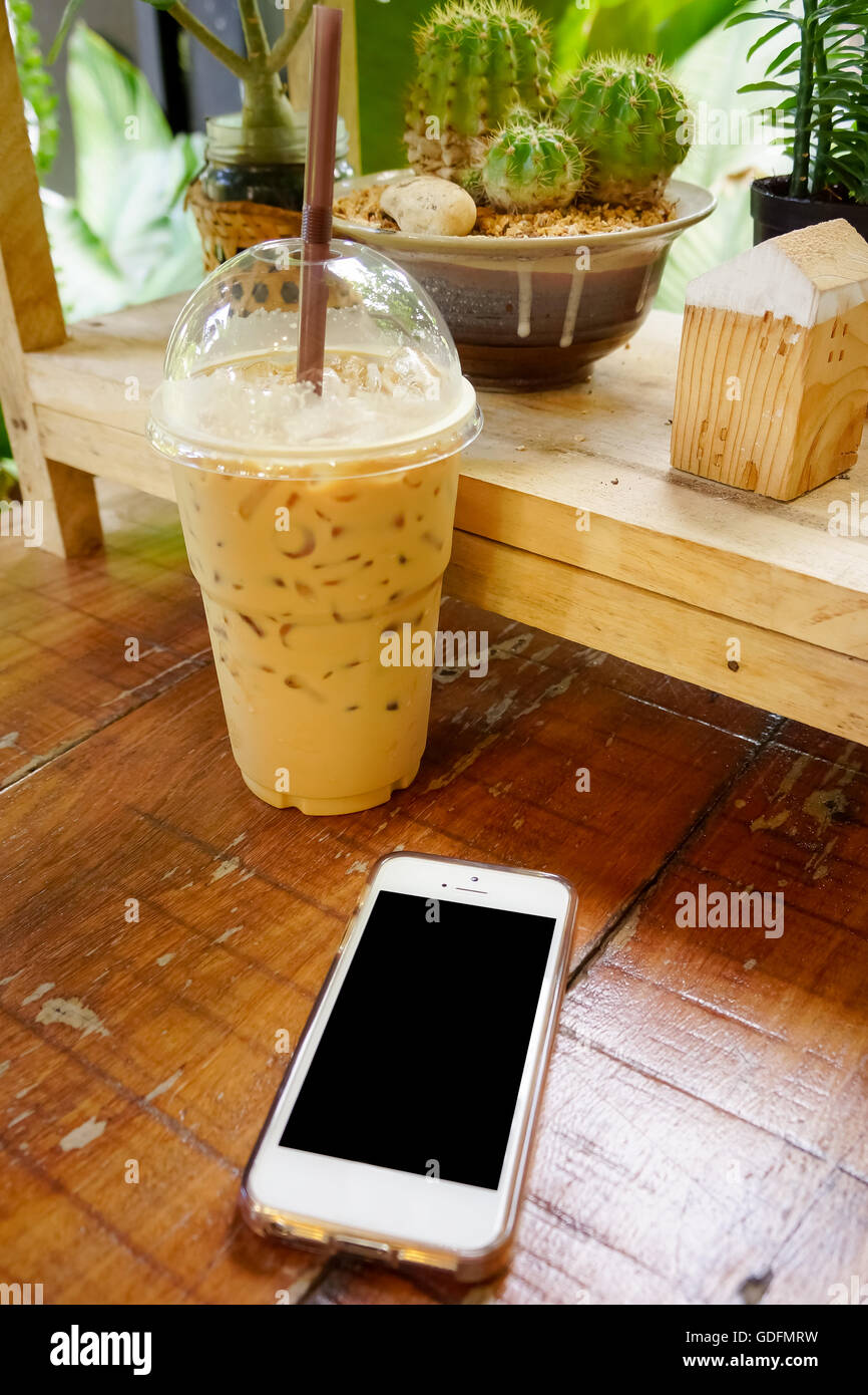 mobile phone with class of iced cappuccino on the table, coffee shop ...