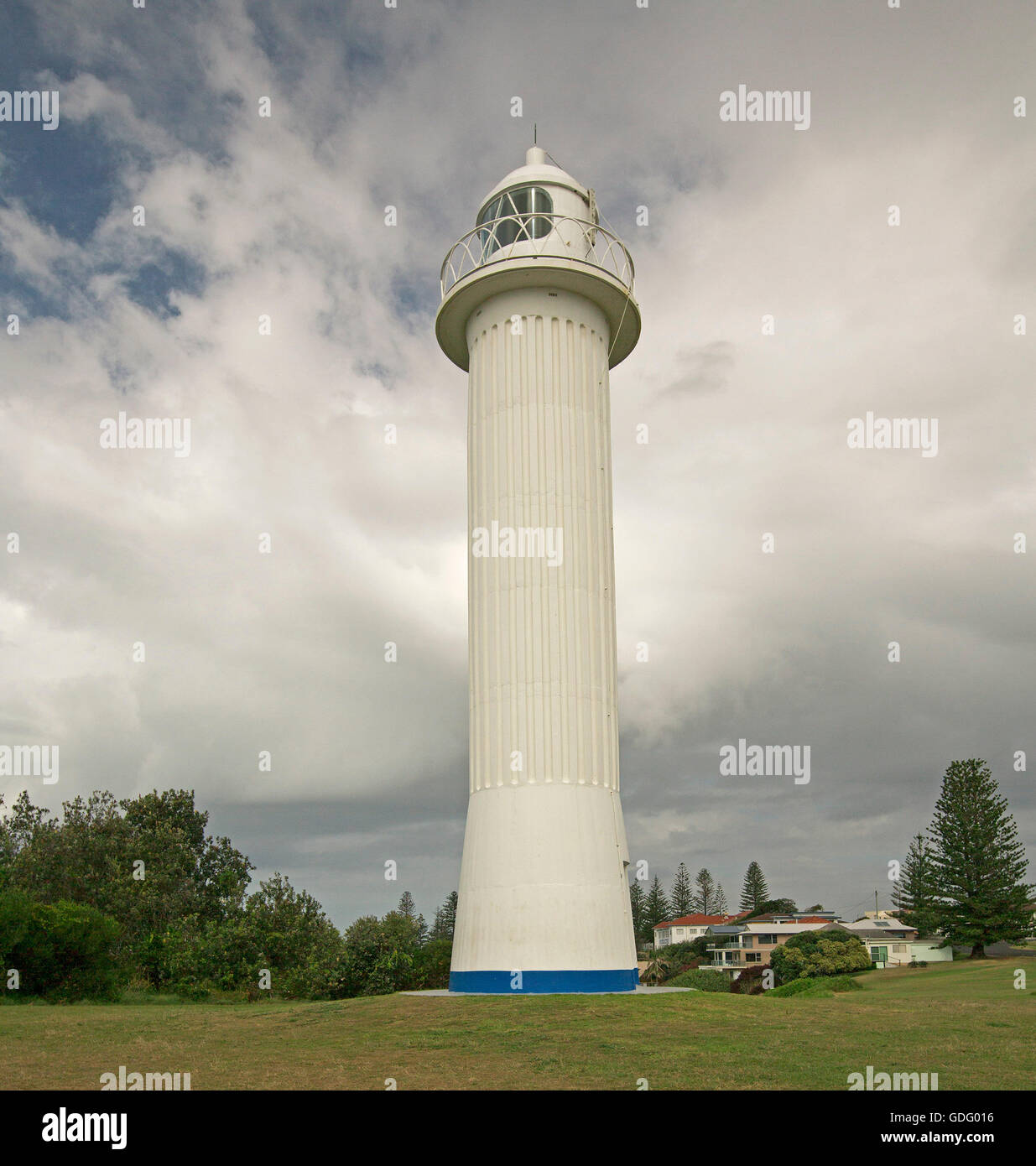 Tall elegant white cylindrical lighthouse rising from grassy hilltop ...