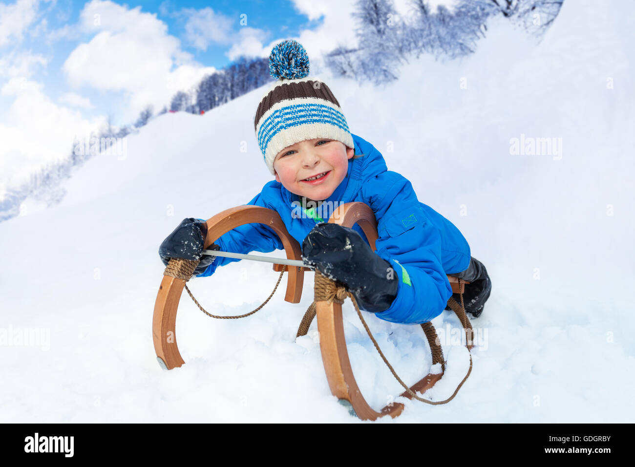 Little boy slide down laying on sledge smile Stock Photo - Alamy