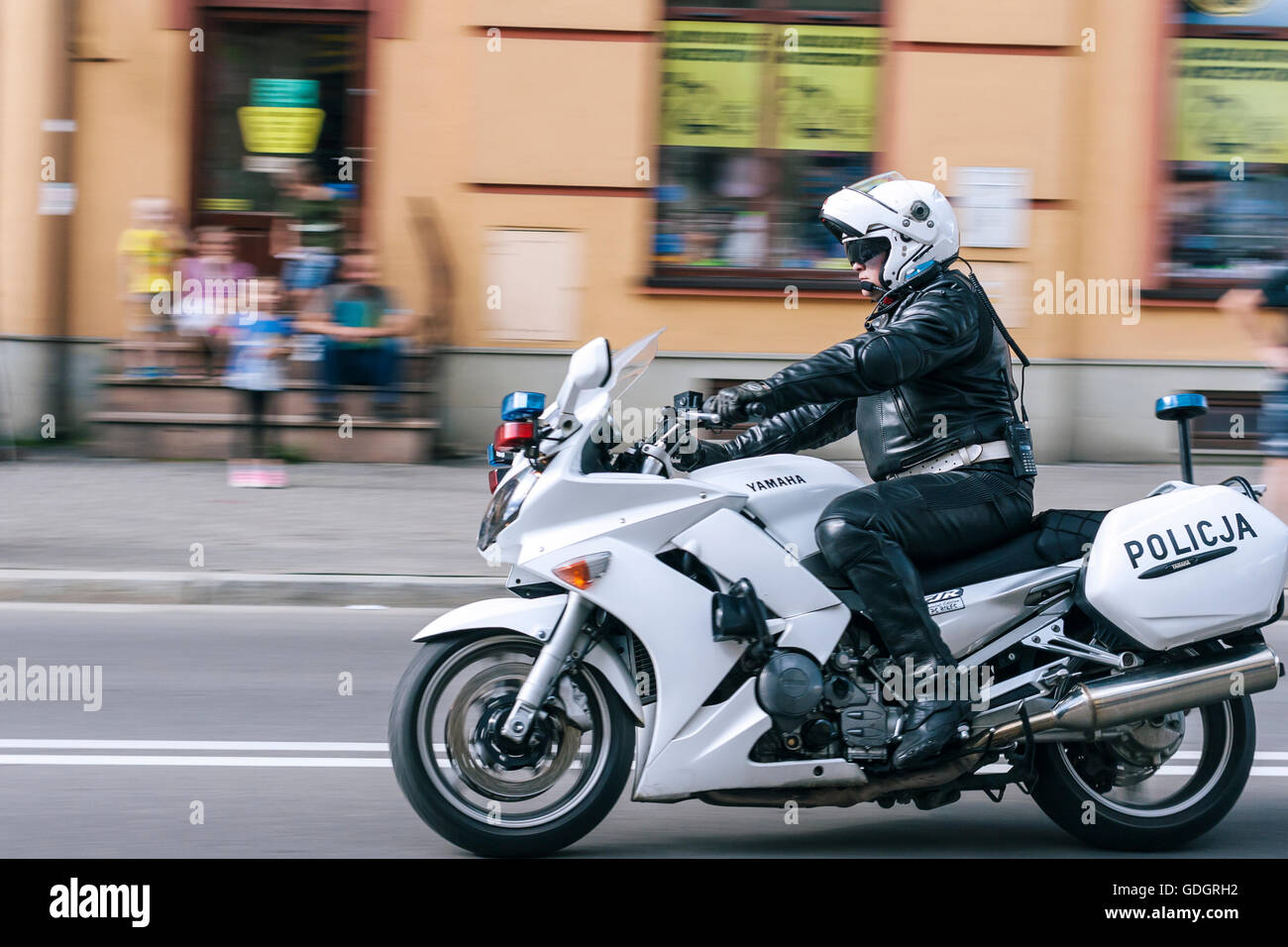Polish Police motorcycle quickly passing people sitting on the steps of ...