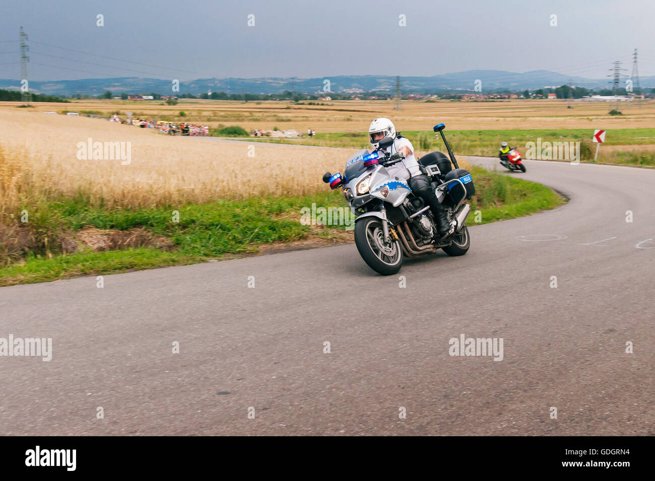 Policeman on the motorcycle passing quickly through fields of grain ...