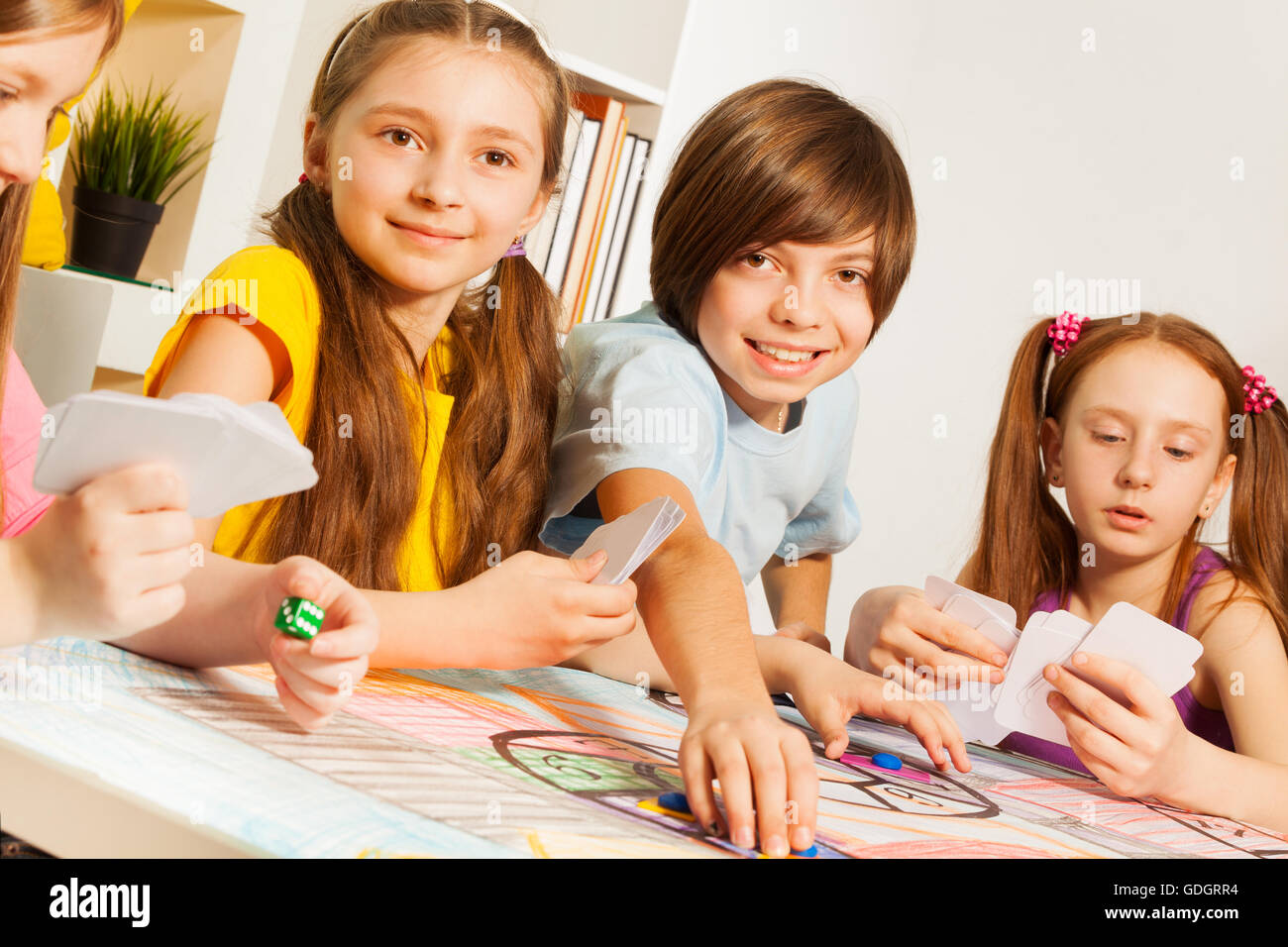 Four friends playing cards sitting at gaming table Stock Photo - Alamy