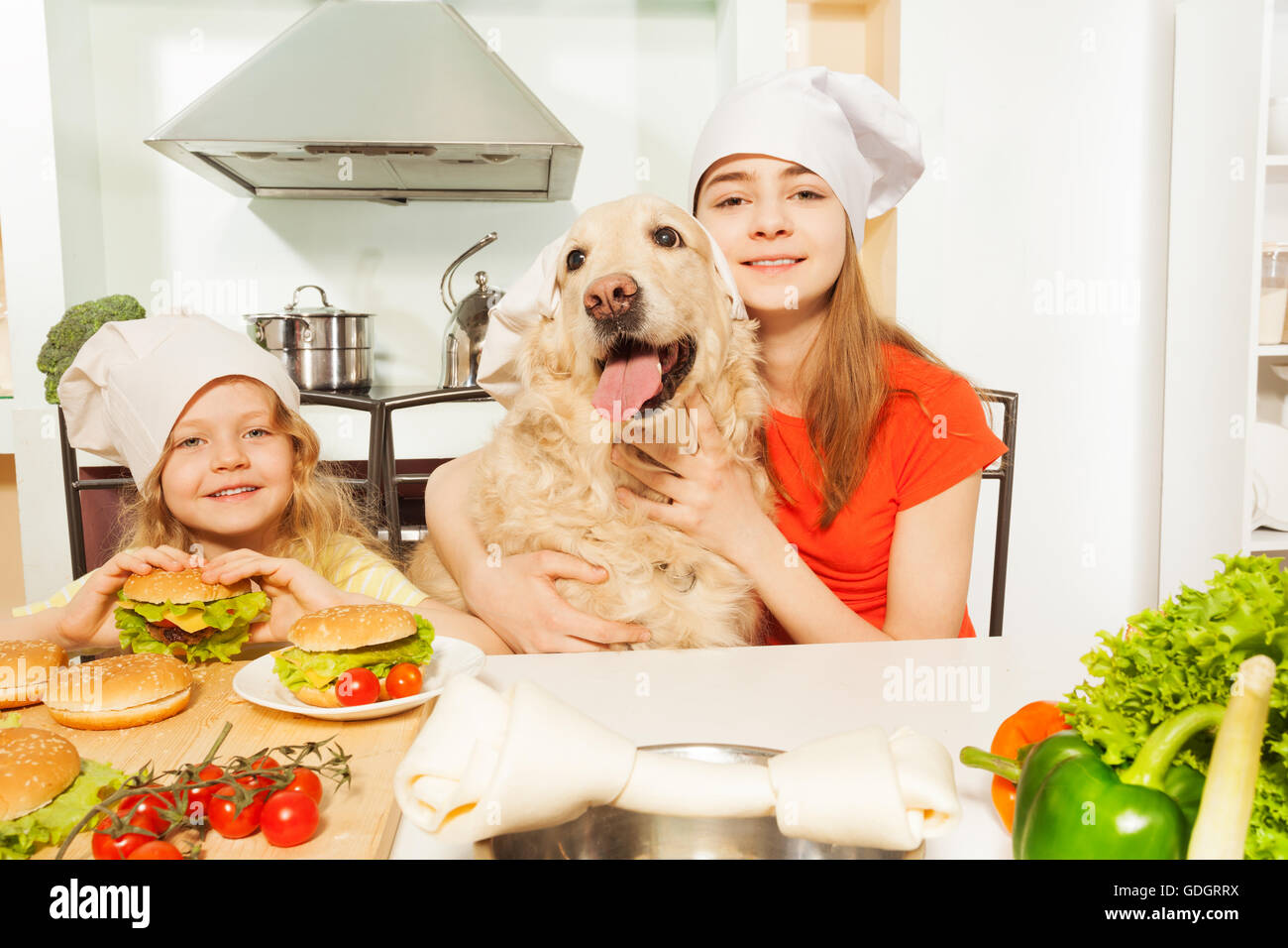 Girls with their pet in cook's hats preparing meal Stock Photo - Alamy