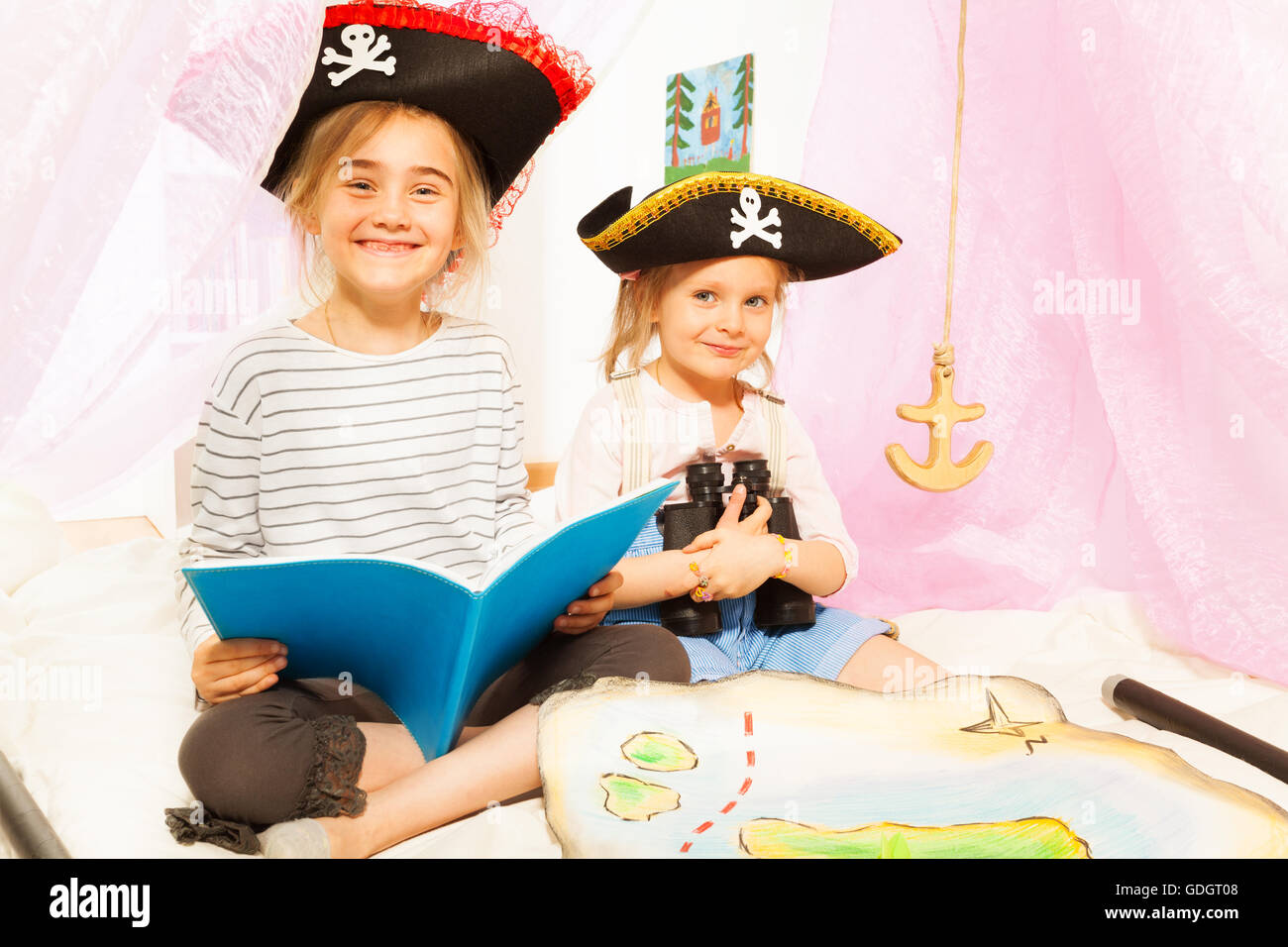 Two cute girls playing pirates, reading fairy-tale Stock Photo - Alamy