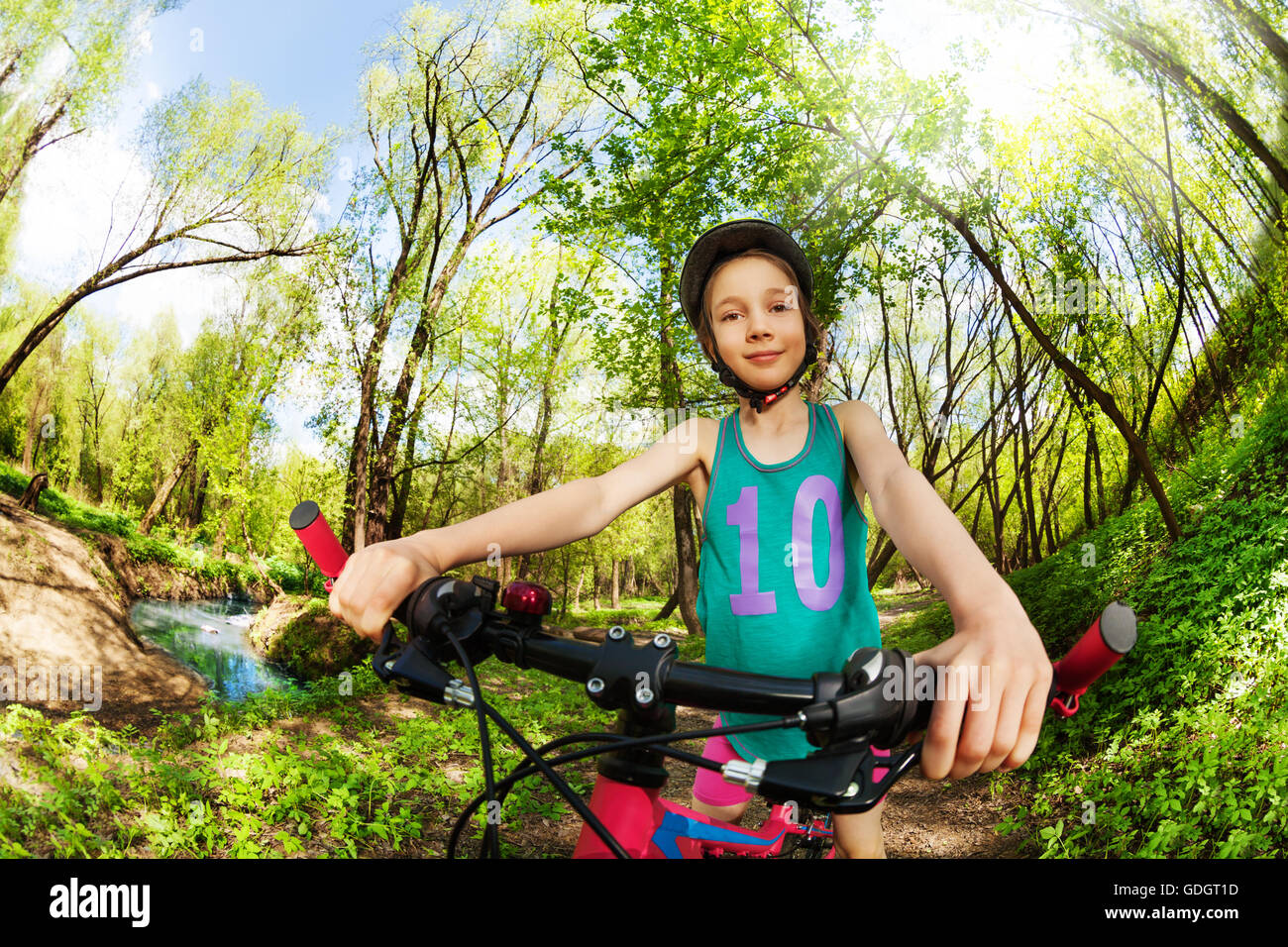 Cute girl cycling by the side of river in woodland Stock Photo - Alamy
