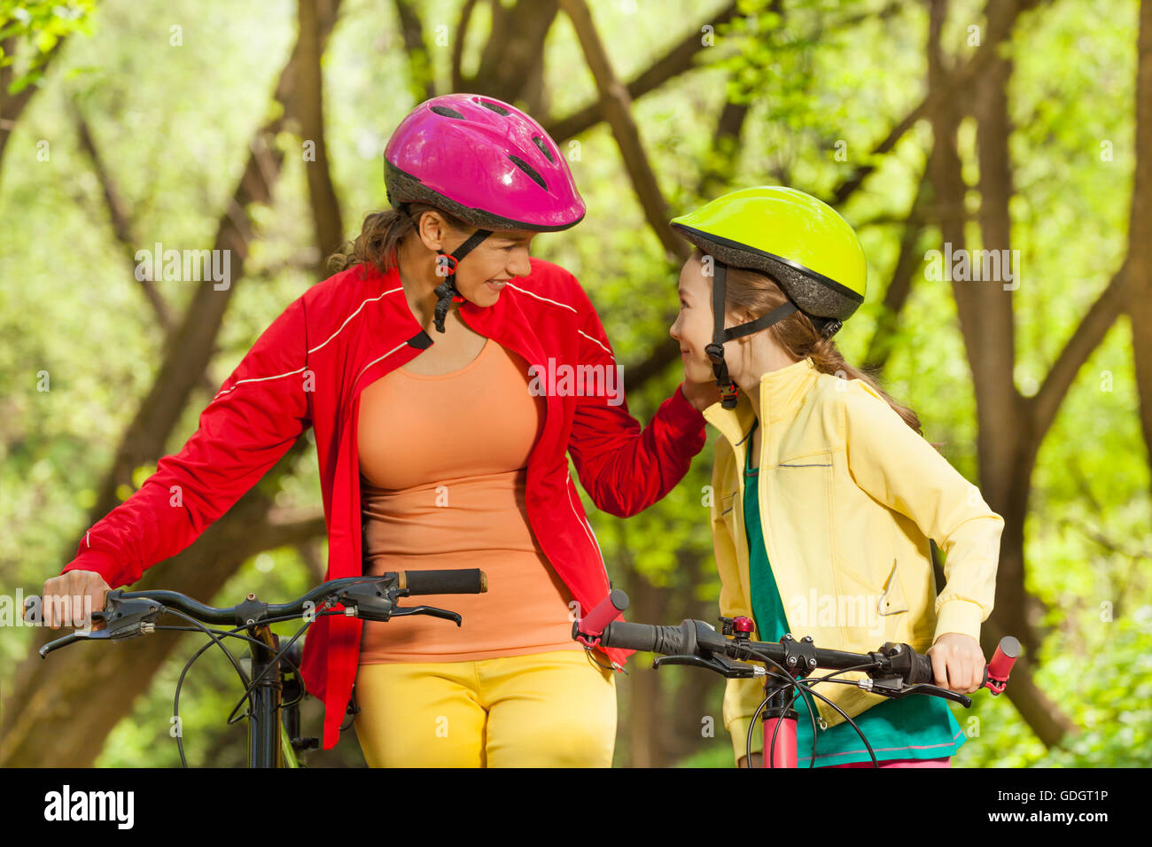 Smiling girl and her mom cycling in spring park Stock Photo - Alamy