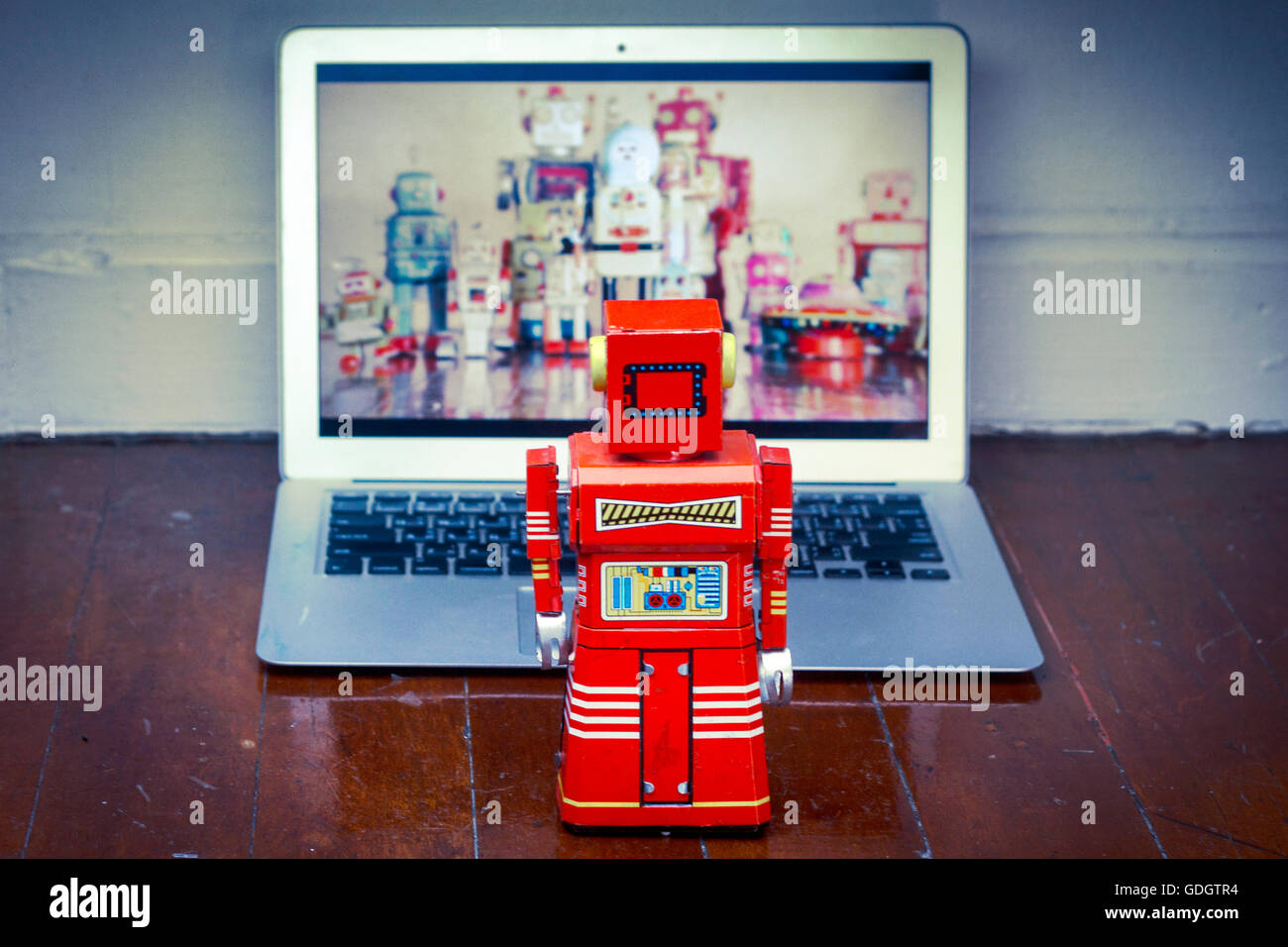 red robot toy watchin a laptop computer Stock Photo - Alamy