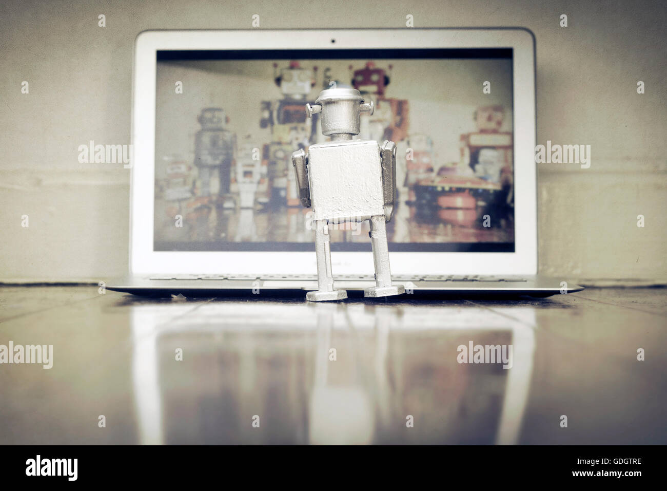 silver robot toy watching tv on a laptop Stock Photo - Alamy