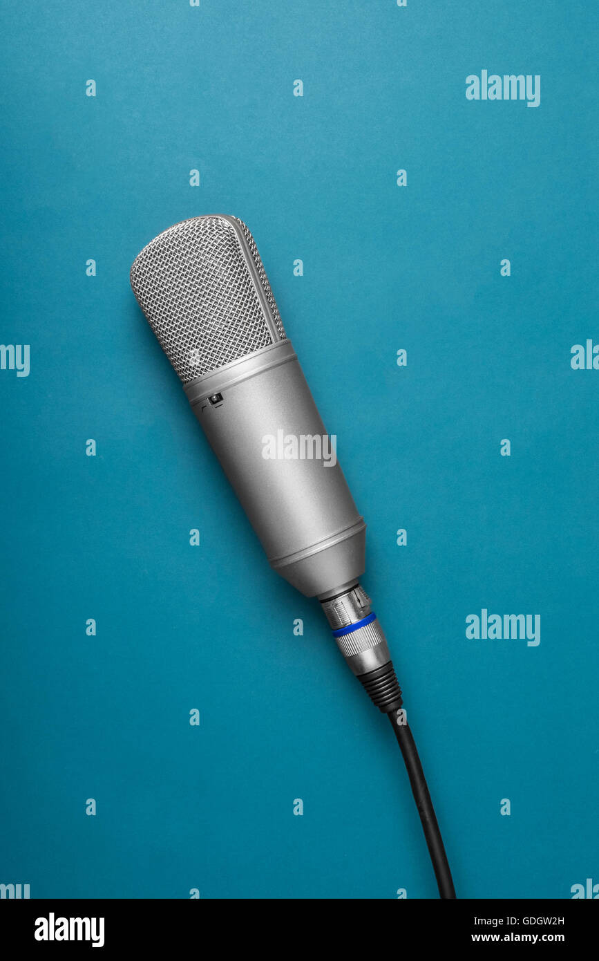 An isolated studio microphone on a blue background Stock Photo - Alamy