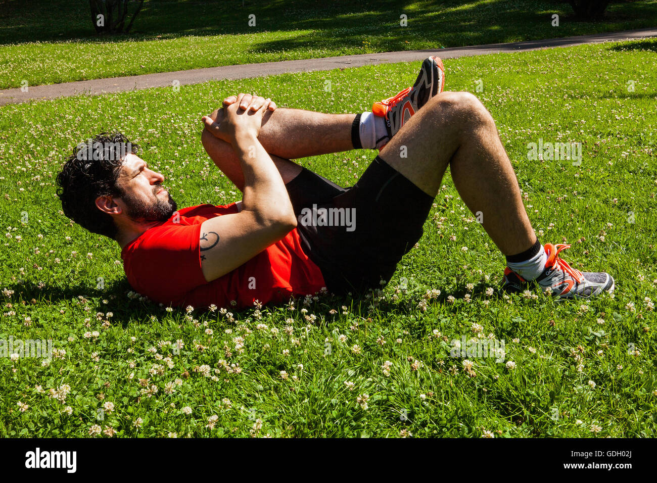 Urban athlete doing stretching exercises on the grass Stock Photo - Alamy