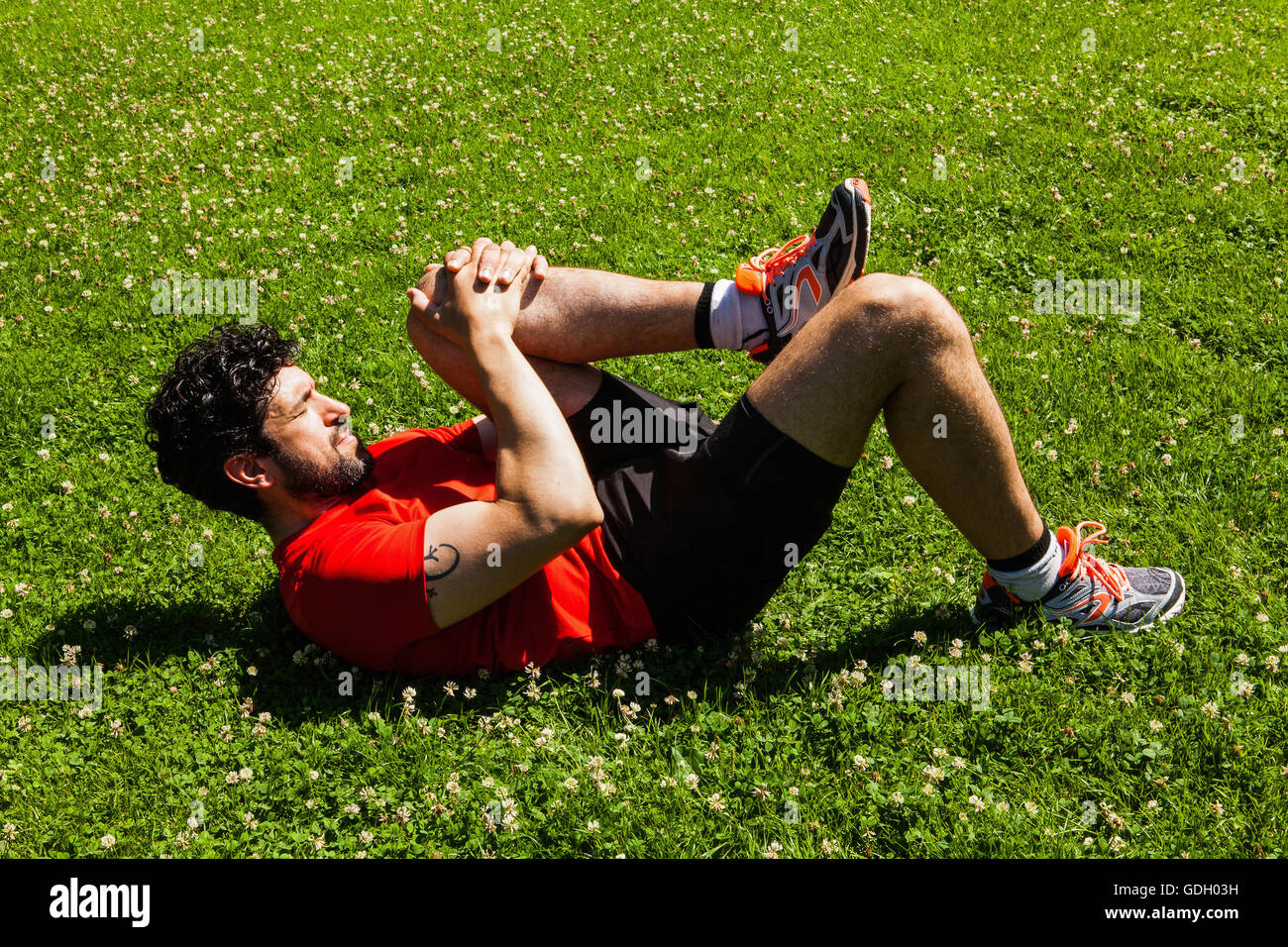 Urban athlete doing stretching exercises on the grass Stock Photo - Alamy