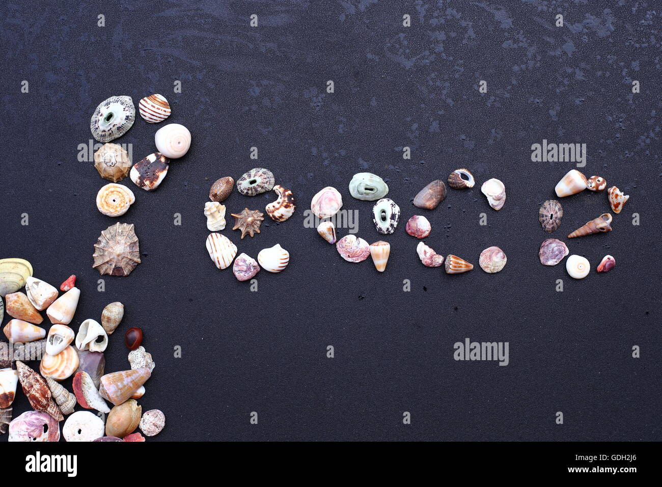The word peace written in seashells against a black background Stock ...