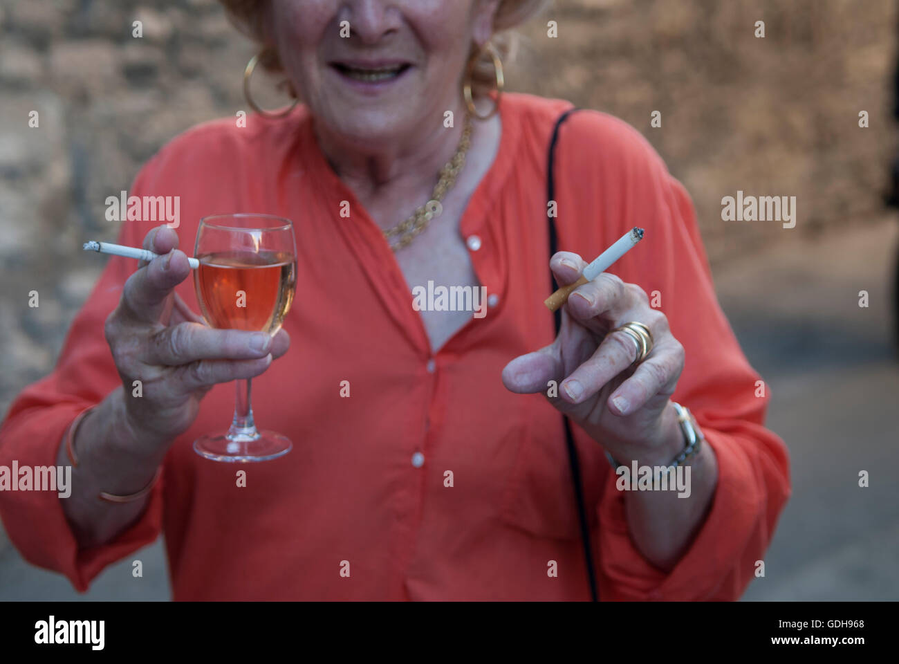 Woman smoking a cigarette drinking alcohol, she has a glass of wine and ...