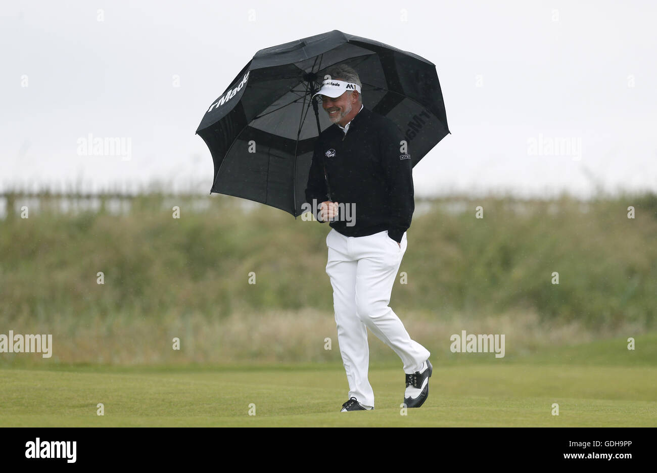Northern Ireland's Darren Clarke shelters from the rain under a ...