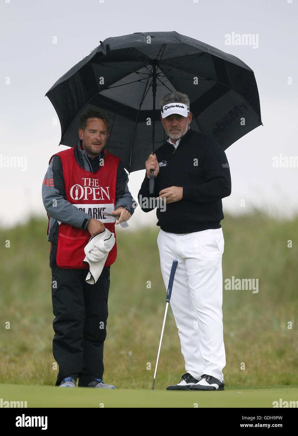 Northern Ireland's Darren Clarke shelters from the rain under a ...