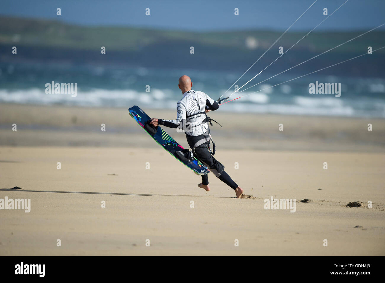 Kite surfer carrying board and flying kite walking down the beach Stock ...