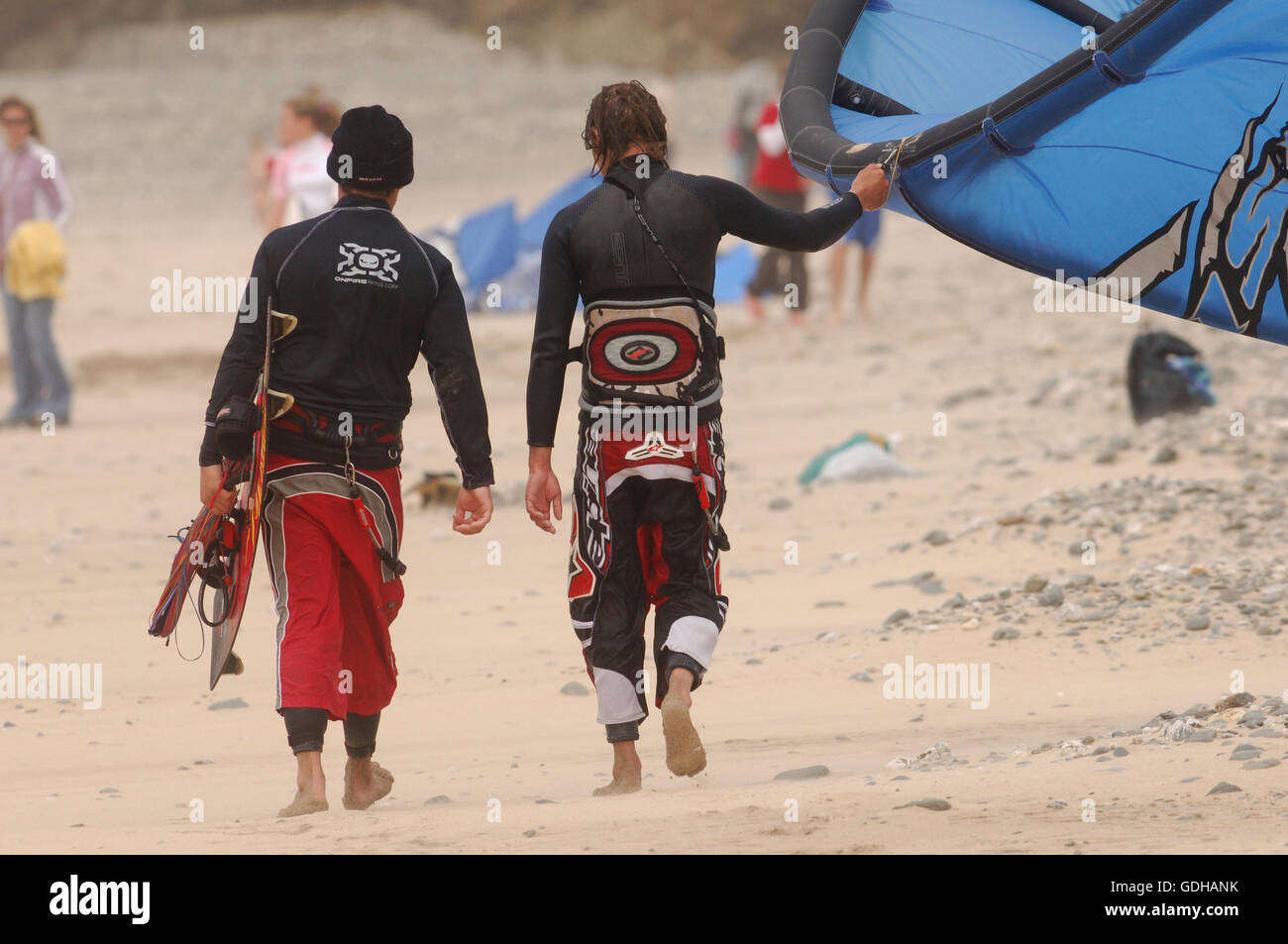 Two kite surfers carrying inflated kite down the beach Stock Photo - Alamy