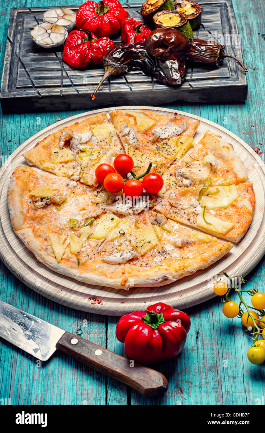 Dining table with pizza and roasted vegetables on stylish cutting board ...