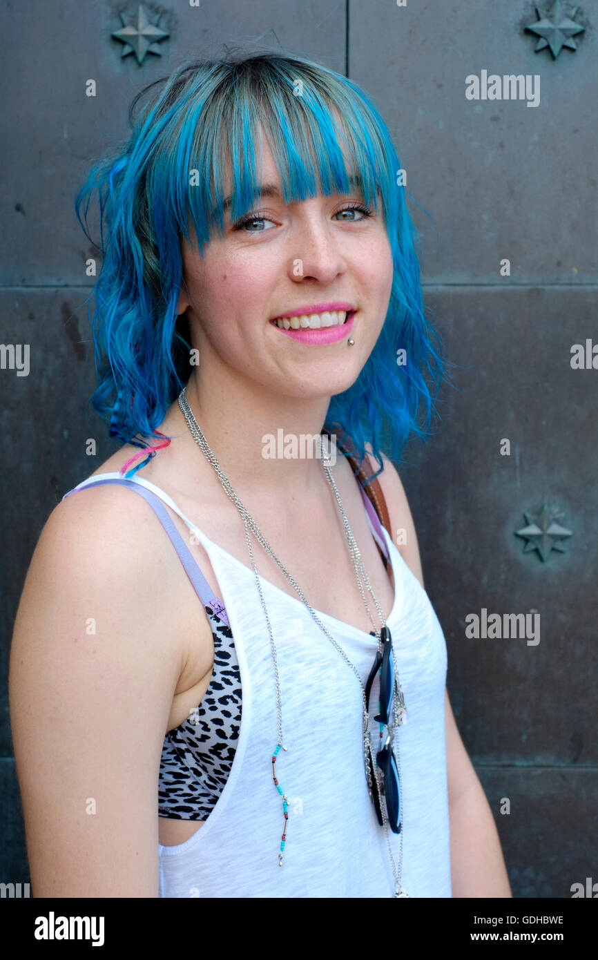 a young pretty smiling female with her hair dyed blue poses for a ...