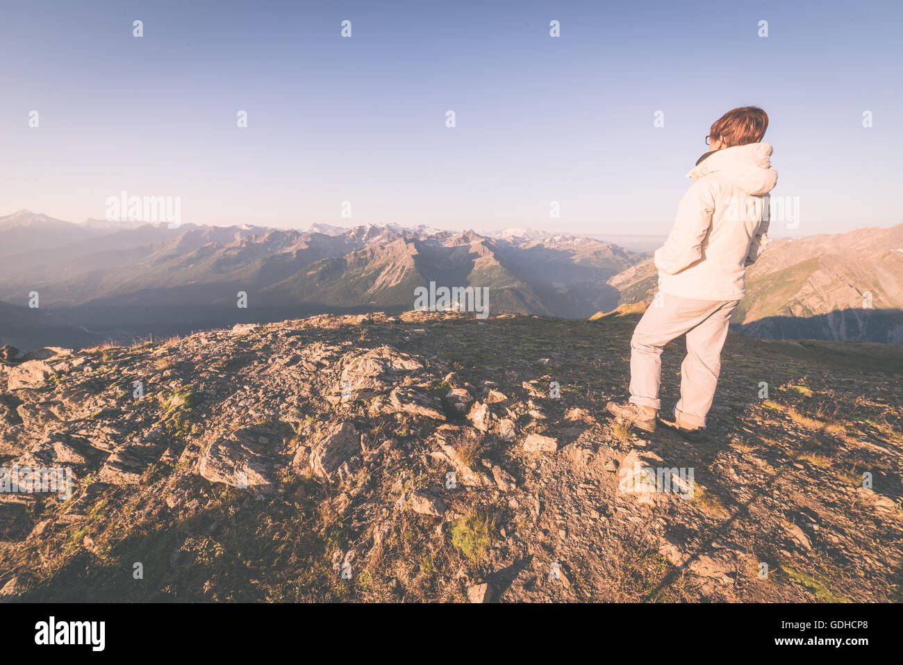 Woman watching stunning sunrise over valleys, ridges and mountain peaks ...
