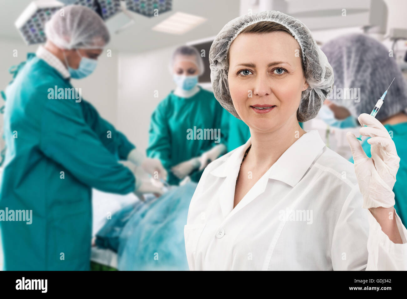 Adult female anesthetist with syringe on the surgery teem background ...
