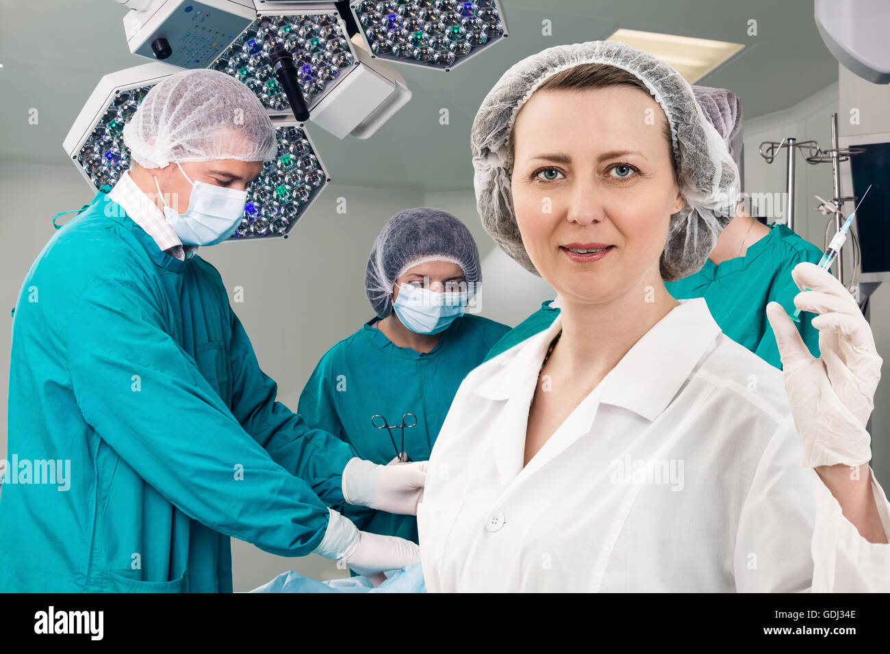 Adult female anesthetist with syringe on the surgery teem background ...