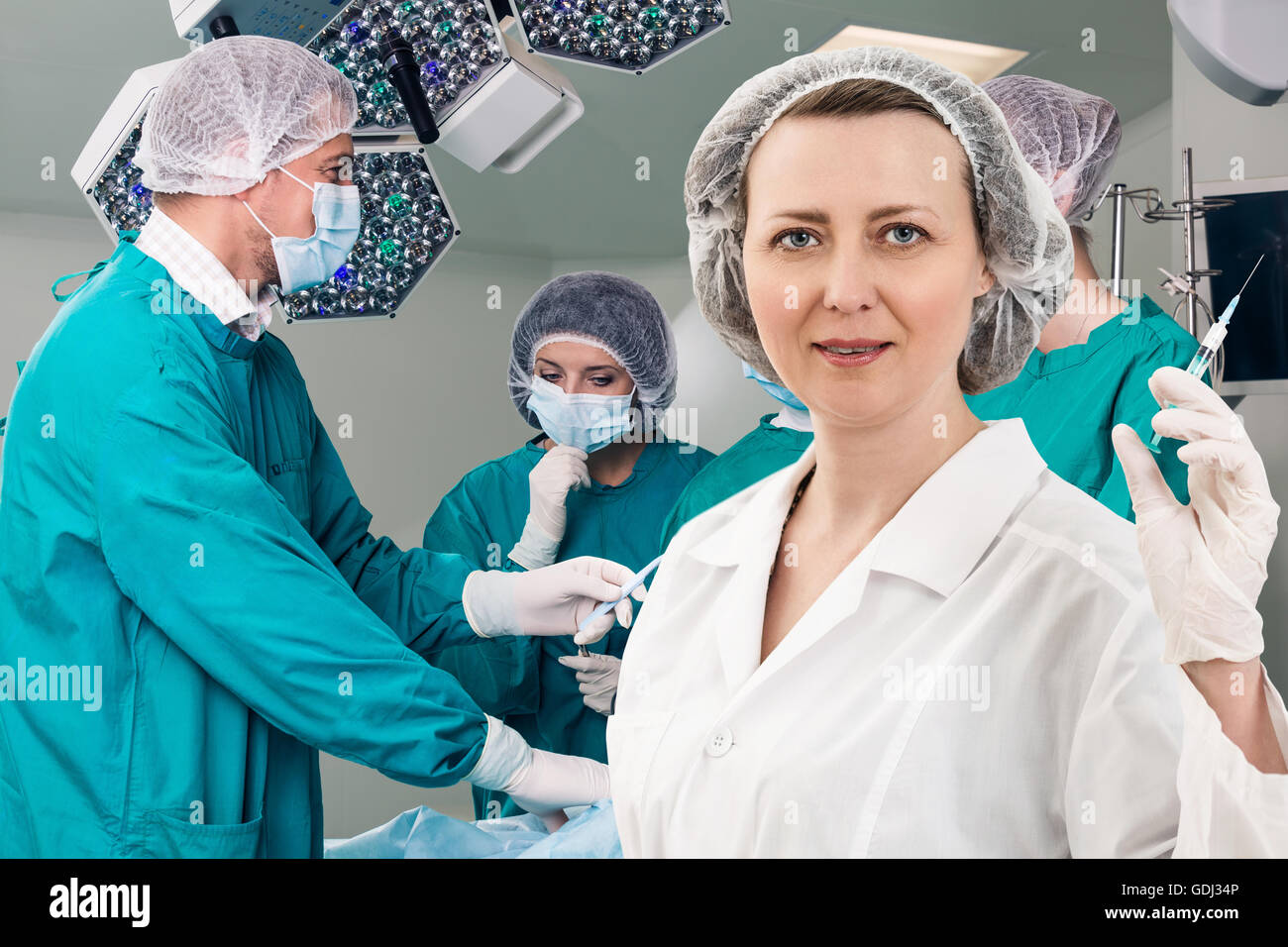 Adult female anesthetist with syringe on the surgery teem background ...