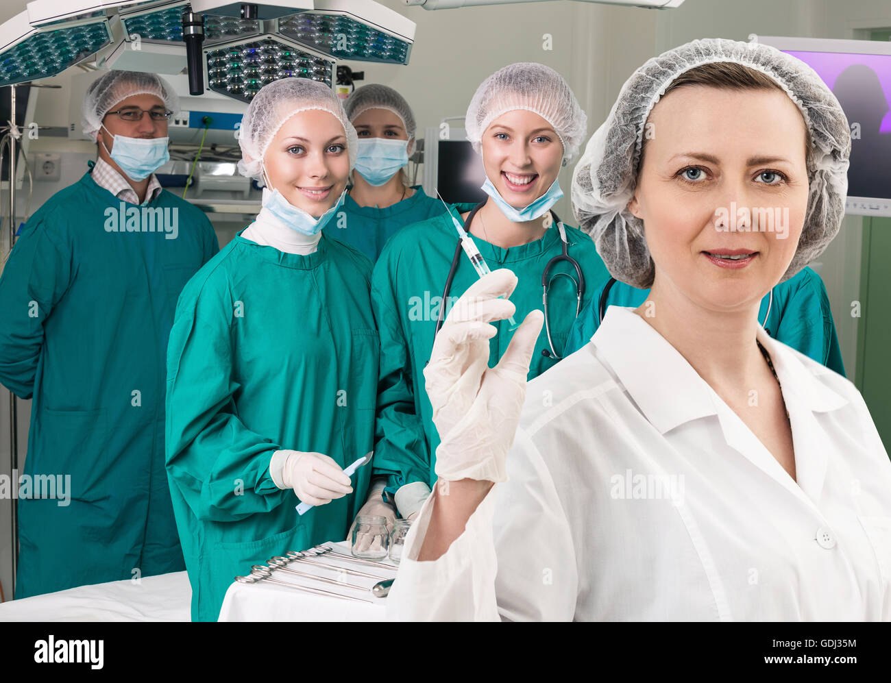 Adult female anesthetist with syringe on the surgery teem background ...