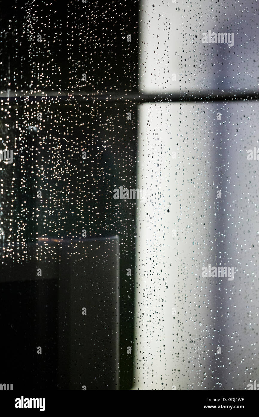 Drops of rain on a window drip down in the evening light Stock Photo ...