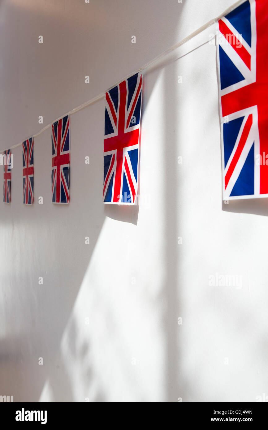 Union Jack flag bunting hanging on an inside white wall Stock Photo - Alamy