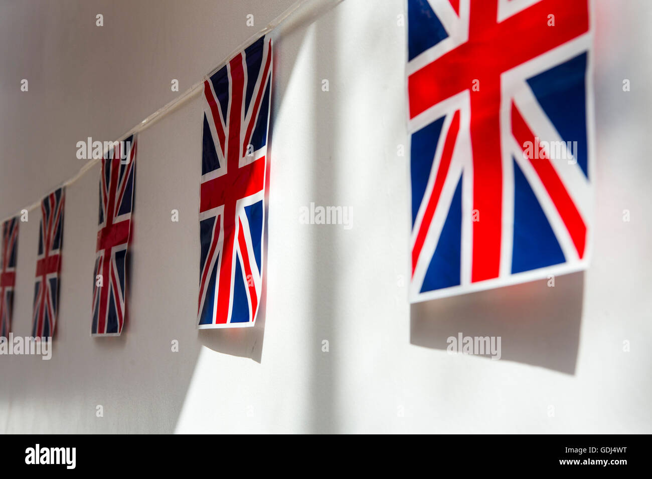 Union Jack flag bunting hanging on an inside white wall Stock Photo - Alamy