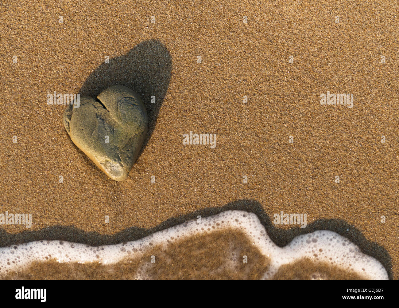Heart shaped rock washed by the sea on a sandy beach Stock Photo - Alamy